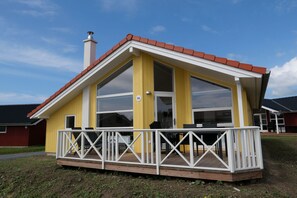 Um edifício amarelo com varanda branca e telhado vermelho.
