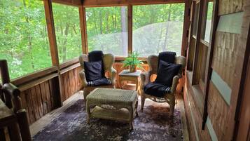Uma cabana de madeira com duas cadeiras de vime, uma mesa pequena e um banco.