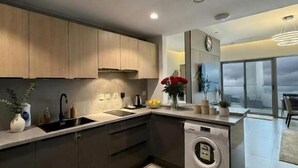 Cozinha moderna com armários escuros, máquina de lavar embutida e uma grande janela com vista.