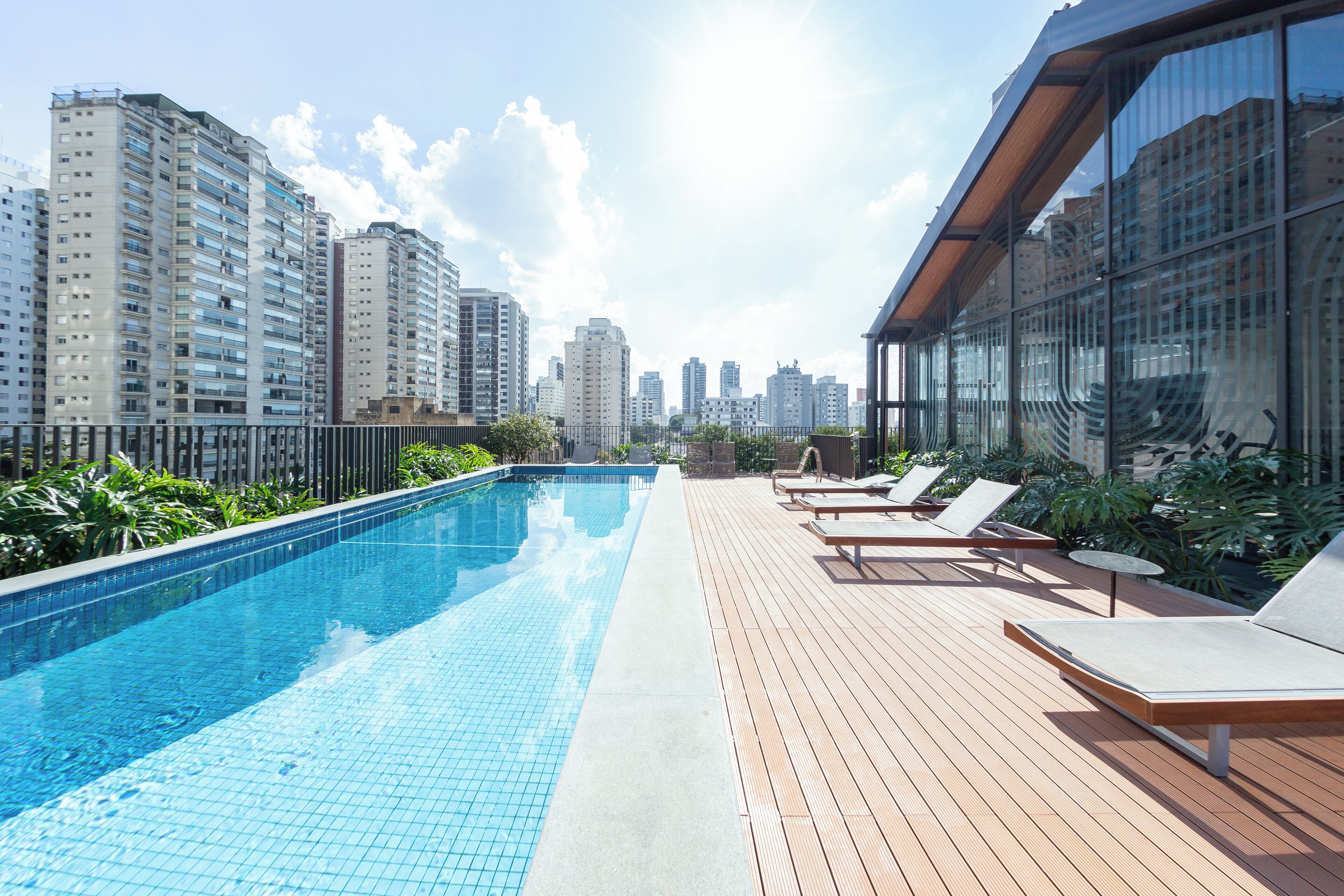Piscina no terraço com espreguiçadeiras e vista para a cidade.