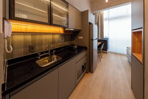 Cozinha moderna com bancada preta, pia de aço inoxidável e forno embutido.
