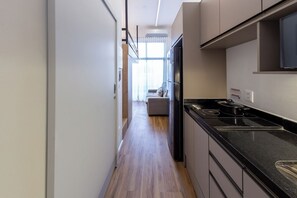 Uma cozinha moderna com bancada preta, eletrodomésticos de aço inoxidável e piso de madeira.