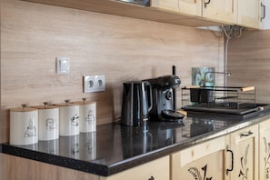 Uma cozinha com armários de madeira, bancada preta, cafeteira e recipientes decorativos.