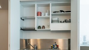 A kitchen with white cabinets, a stainless steel sink, and a countertop with various kitchen items.