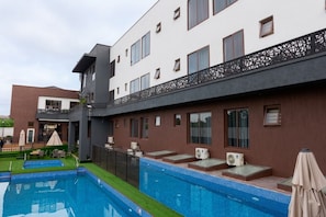 Um edifício moderno com piscina, área de estar externa e várias janelas.
