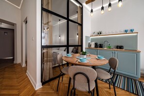 Uma cozinha moderna com área de jantar, apresentando uma mesa redonda de madeira, cadeiras e um tapete listrado.