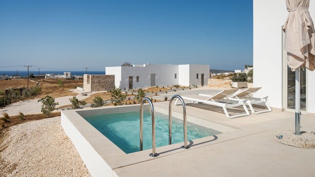 A modern outdoor pool area with lounge chairs and a clear view of the sea.