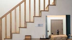 Quarto com escada de madeira, cama com uma revista, escrivaninha com um espelho e bacia de pedra.