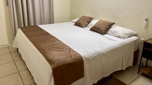 Uma cama de solteiro com um edredom marrom e branco, um travesseiro branco e um travesseiro marrom.