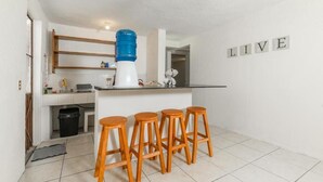 Uma cozinha com dispensador de água, área com banquetas de bar e um letreiro 'LIVE' na parede.