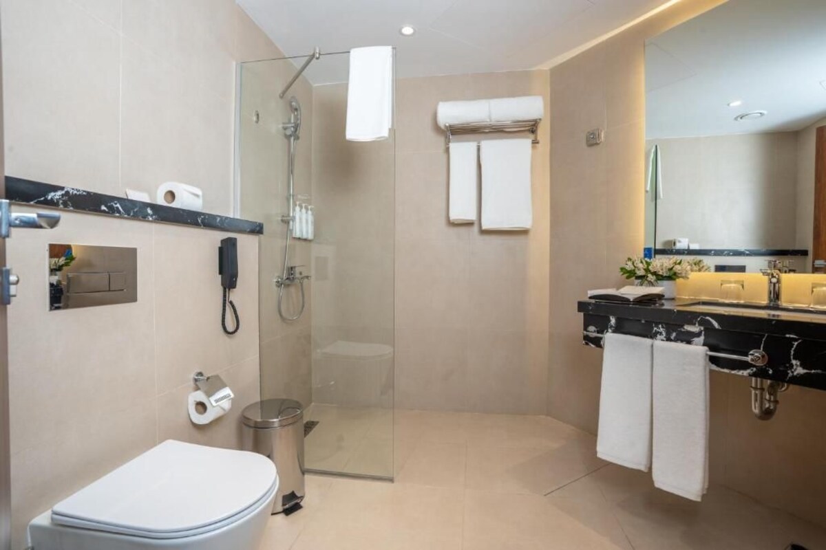 Uma casa de banho moderna com sanita, chuveiro e lavatório.