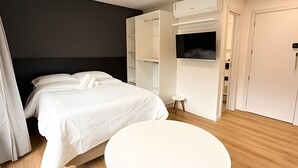 Quarto de hotel moderno com uma cama, uma pequena mesa redonda e armários embutidos.