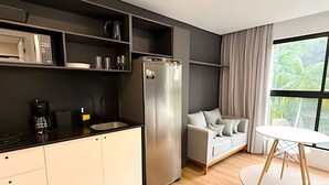Uma cozinha moderna com geladeira, cafeteira e área de jantar com mesa e cadeiras.