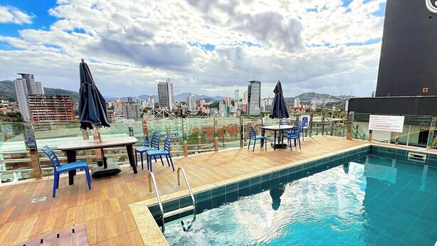 Uma área de piscina no terraço com vista para o horizonte da cidade, incluindo uma ponte e edifícios.