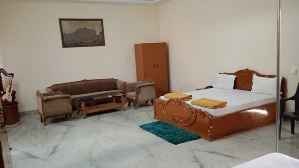 Um quarto com uma cama, um sofá, um armário de madeira e uma mesa pequena.