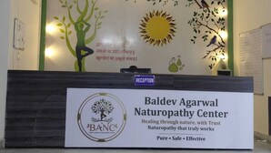 Balcão de atendimento no Centro de Naturopatia Baldev Agarwal, com sinalização indicando ser a área de recepção.