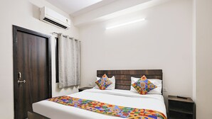 Quarto de hotel com cama, mesa de cabeceira, ar condicionado e porta.