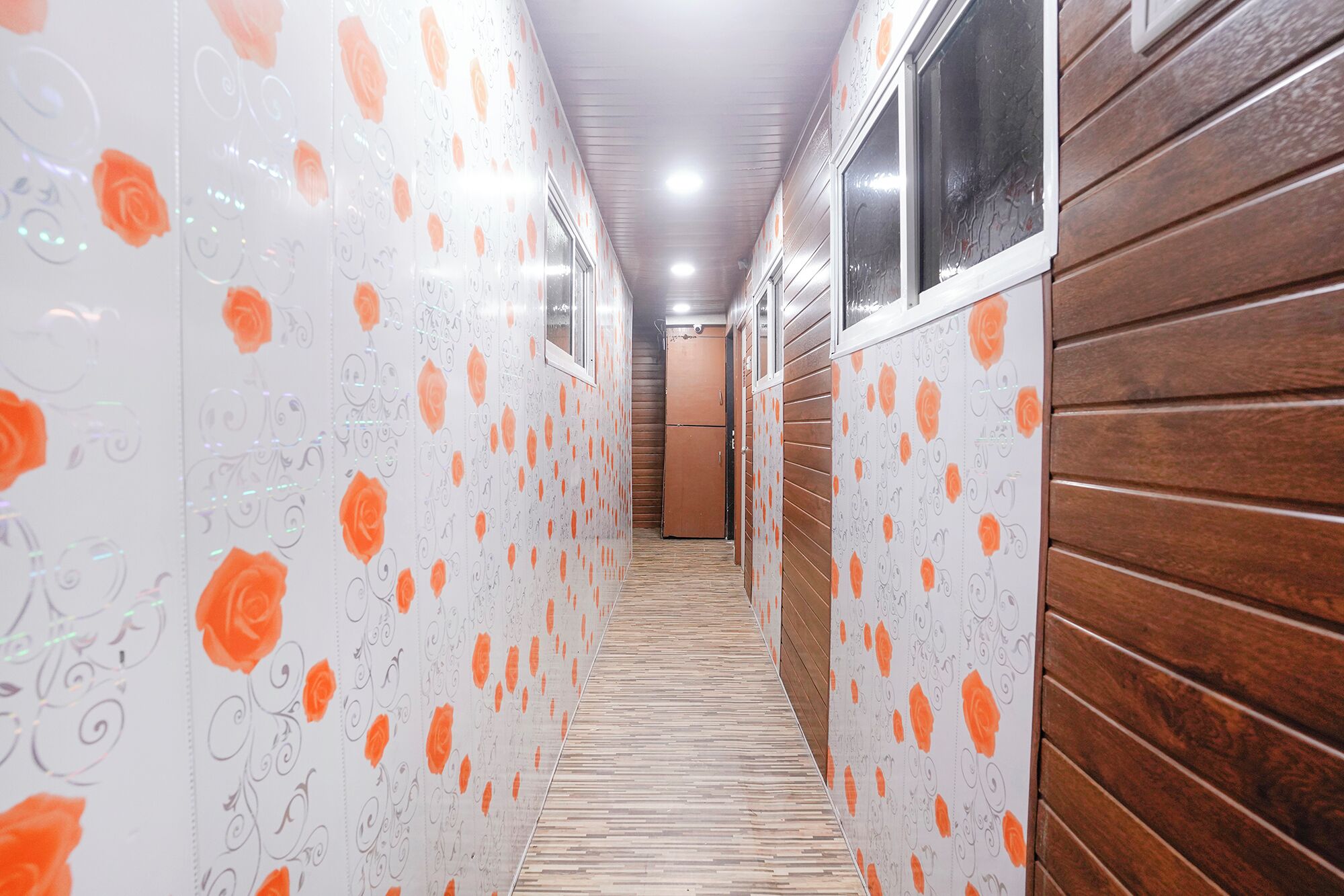Um corredor estreito com papel de parede estampado e lambrisagem de madeira.