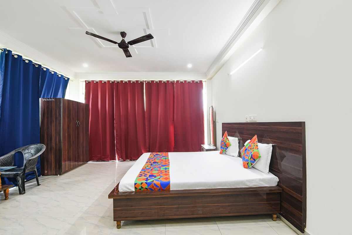 Quarto com cama, ventilador de teto, televisão e janela com cortinas.
