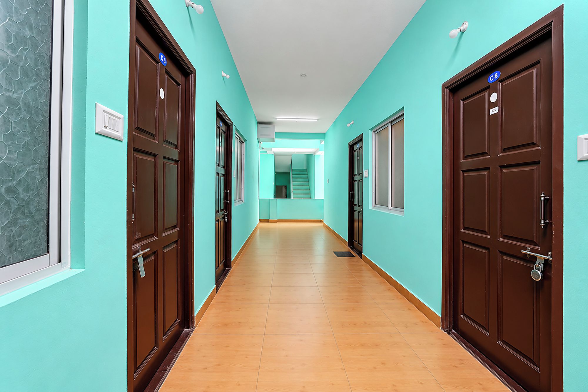Corredor com paredes verde-água, portas de madeira e chão de azulejos.