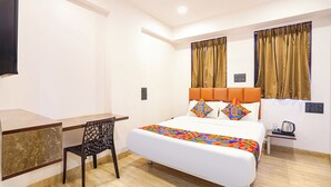 Quarto de hotel com cama, escrivaninha, cadeira, cafeteira e cortinas.
