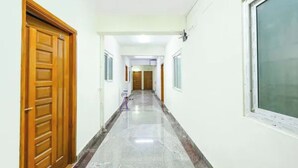Um corredor com portas em ambos os lados, piso de azulejos e uma janela à direita.