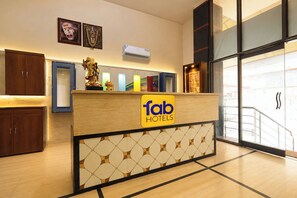 Uma receção com o letreiro 'fab hotels', armários de madeira, uma estátua e uma janela grande com vista.