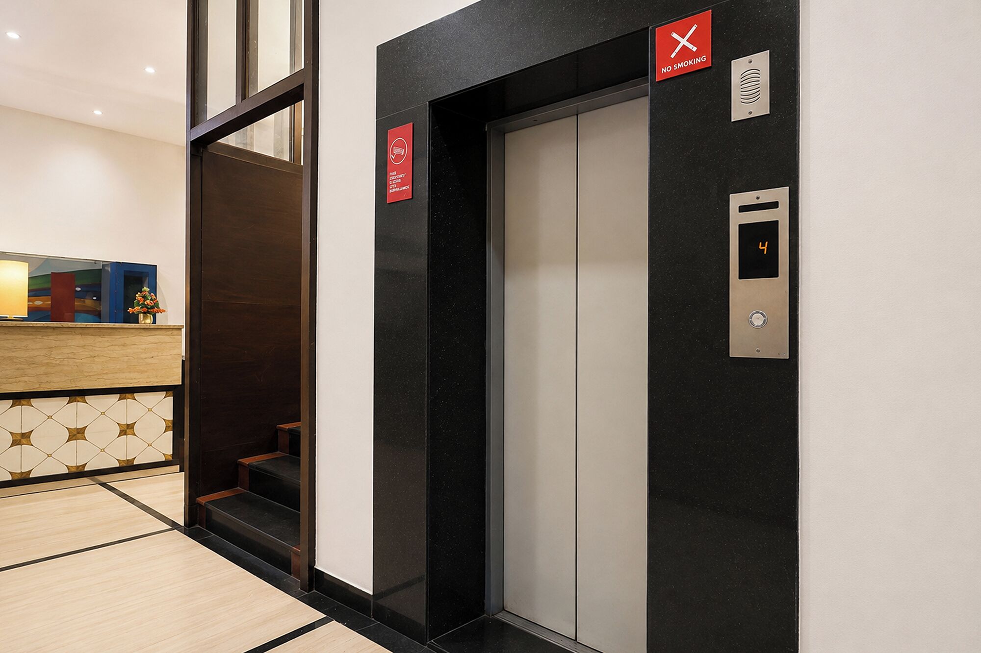 Um elevador com visor digital, placa de 'Proibido Fumar' e sinal de segurança contra incêndio.