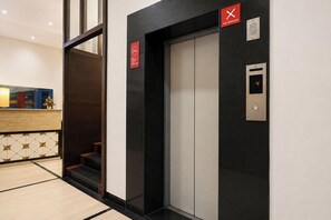Um elevador com visor digital, placa de 'Proibido Fumar' e sinal de segurança contra incêndio.