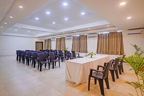 Uma sala de conferências com uma mesa comprida, cadeiras e luminárias no teto.