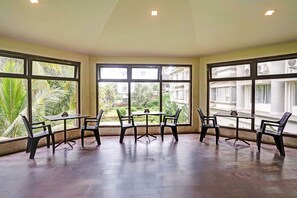Um quarto com grandes janelas, piso de azulejos e uma mesa com cadeiras.