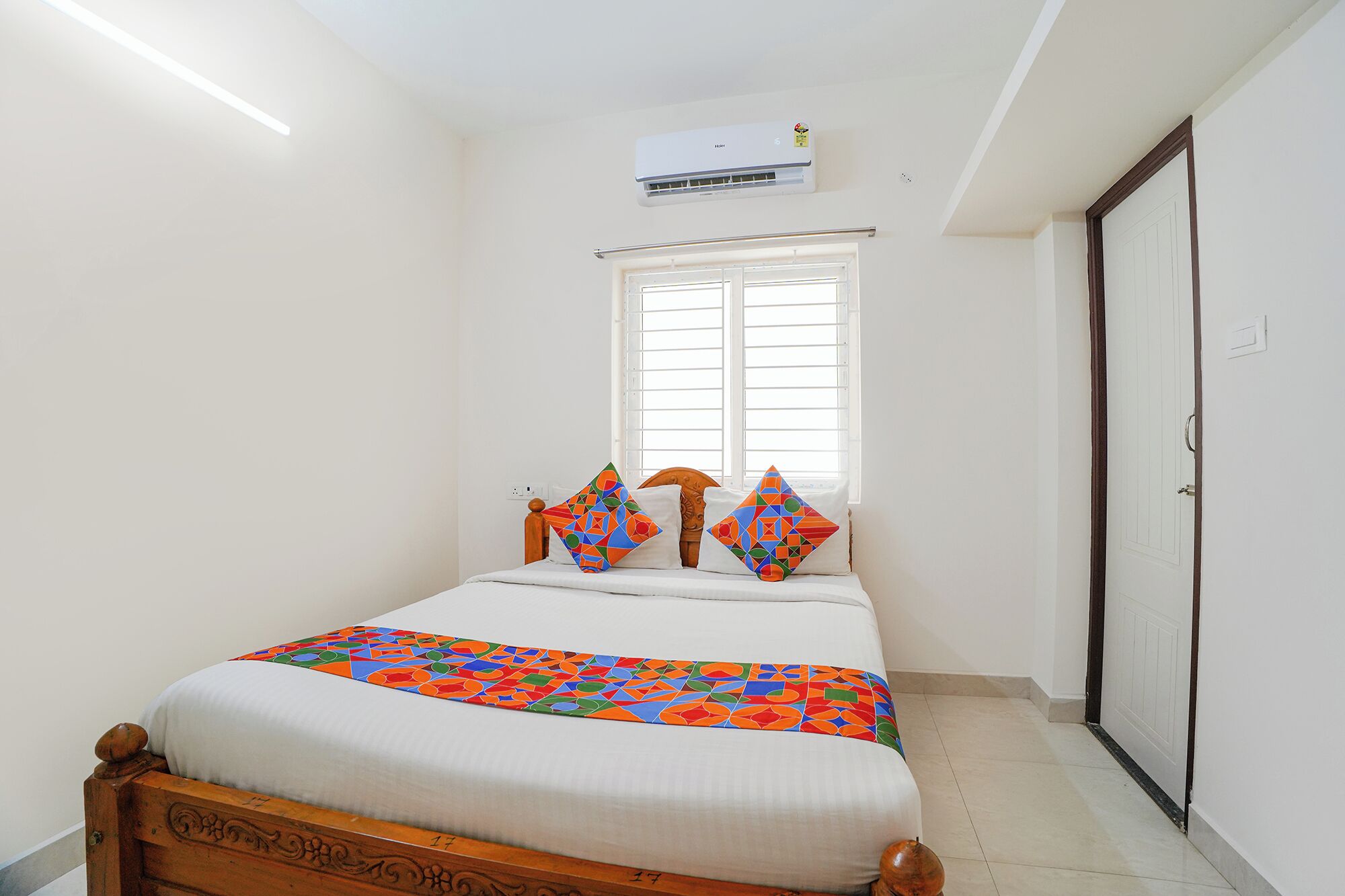 Quarto com cama, janela, ar condicionado e porta.