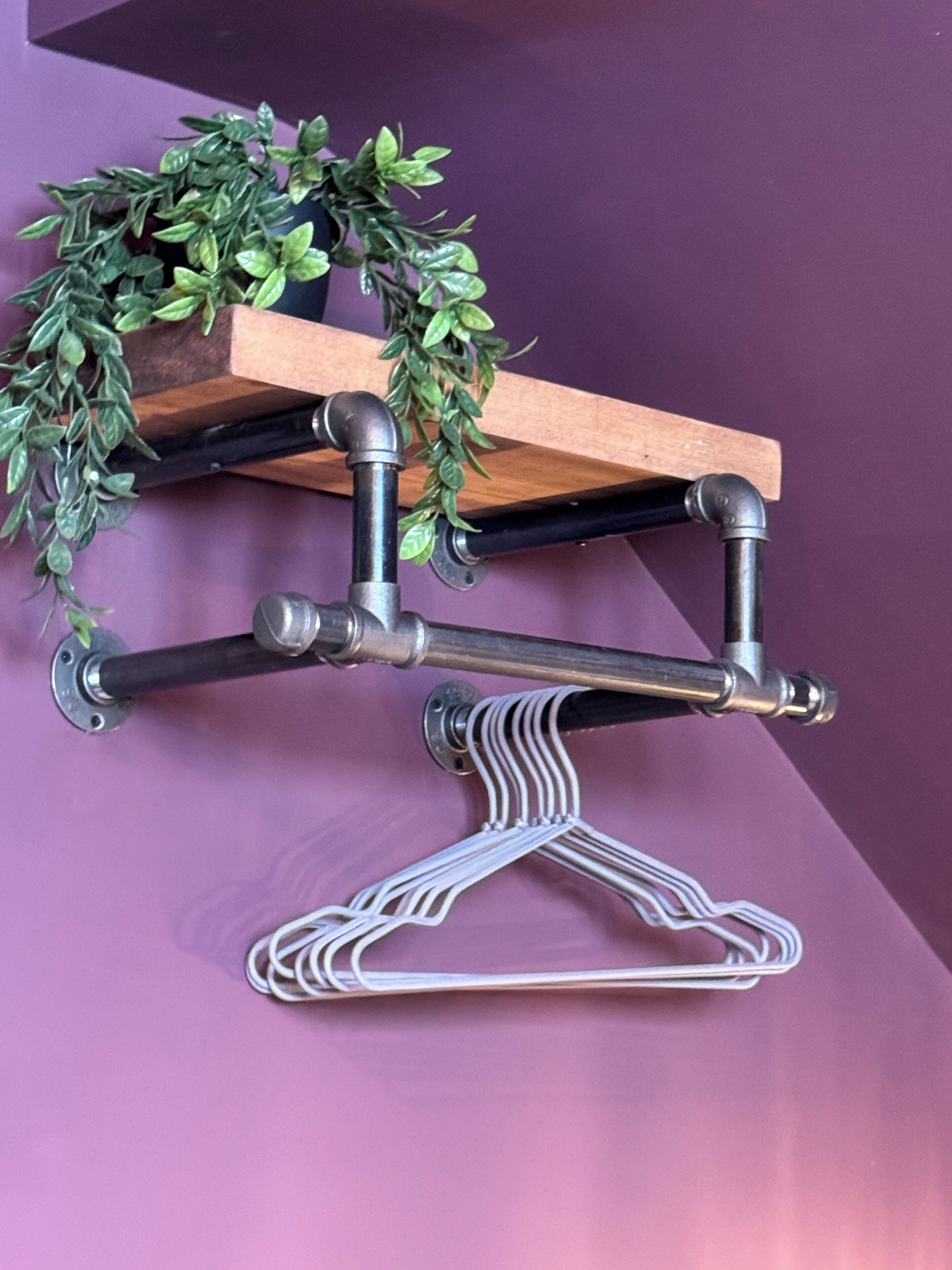 Uma estante de metal com prateleira de madeira onde está um vaso com planta.