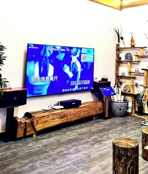 Uma sala de estar moderna com uma televisão de tela plana na parede, um banco de madeira e uma estante decorativa com diversos objetos.