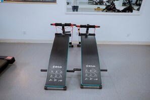 Dois bancos de exercícios com faixas de resistência em um espaço com espelho e janela.