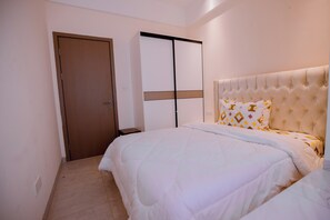Quarto com cama, guarda-roupa e armário fixo na parede.