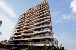 Um edifício com várias andares, varandas e um céu claro.