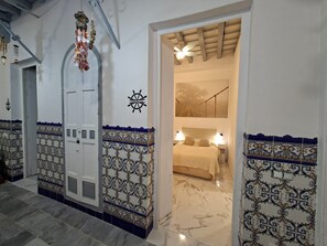 Quarto de hotel com cama, mesas de cabeceira, ventoinha no teto e vista para uma ponte pela janela.