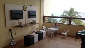 Quarto com mesa de bilhar, guitarra, televisão e vista para o mar.