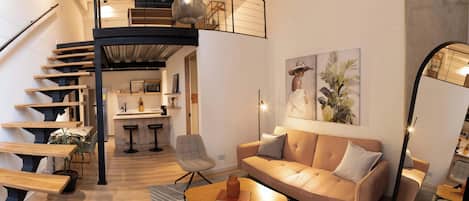 Um interior moderno com escada, sofá, área de refeições e cozinha.