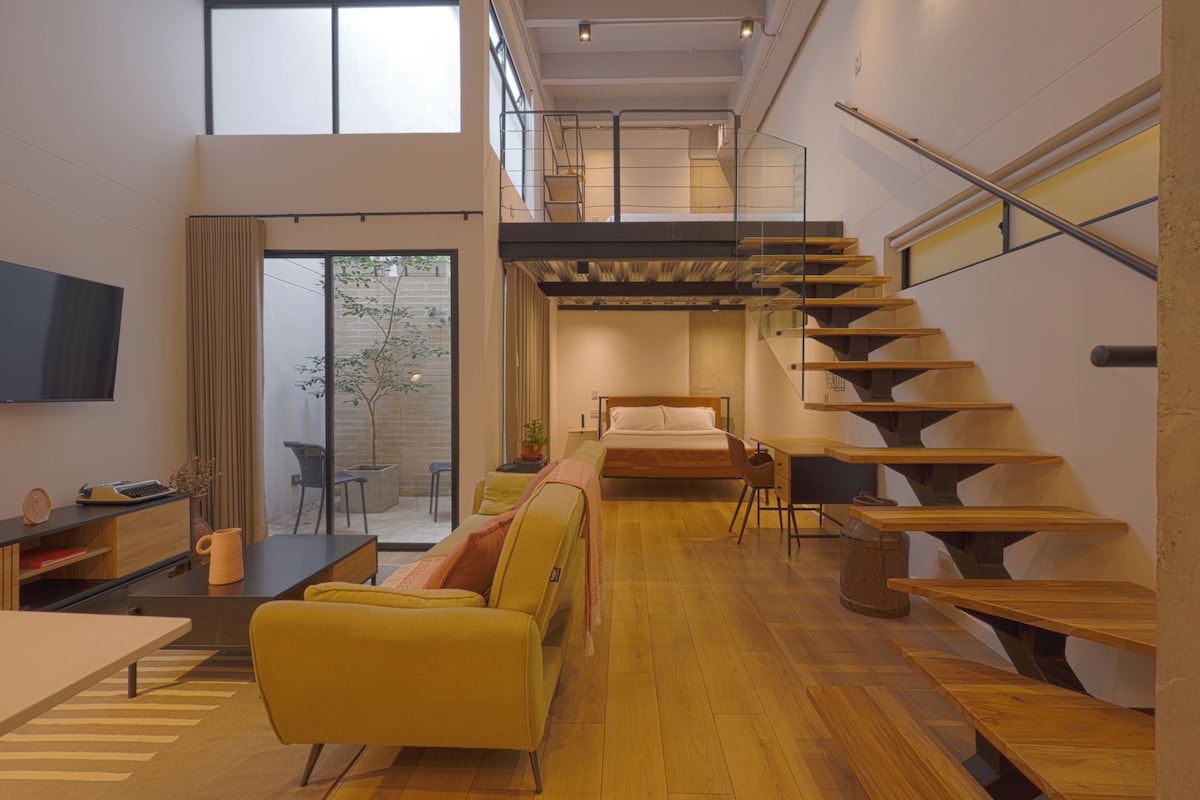 Um interior moderno com um quarto em mezanino, uma área de jantar e uma escada.