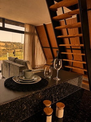 Um interior moderno com área de refeições, bancada de mármore, sofá e vista para o exterior.