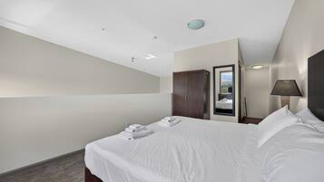 Quarto de hotel com uma cama grande, um guarda-roupa, um espelho e vista para a cidade.