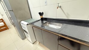 Uma cozinha com pia de aço inoxidável, lava-louças e geladeira.