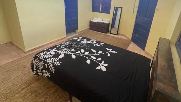 Um quarto com uma cama, uma pequena mesa e um guarda-roupa.