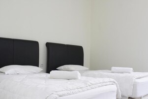 Quarto de hotel com duas camas, cada uma com roupa de cama branca e cabeceiras pretas.