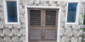 A double door with horizontal slats, flanked by two windows with white frames.