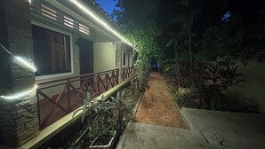 Um caminho leva a um edifício com fachada de pedra e guarda-corpo vermelho.