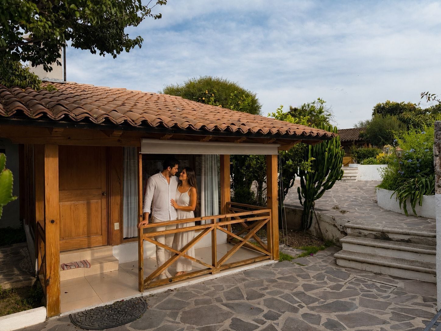 Uma construção de madeira com telhado de telhas, porta e pequena varanda.