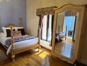 Uma cama de dossel tradicional com cortina, um espelho grande e vista para uma varanda.